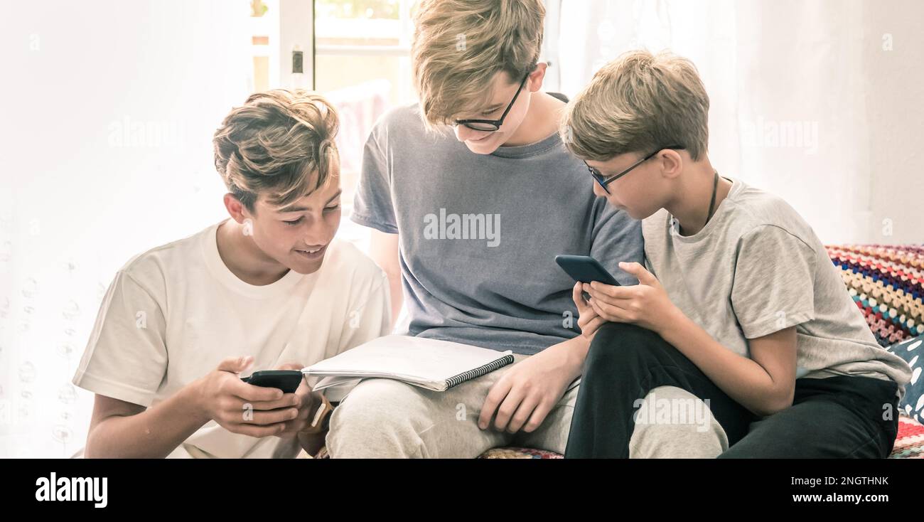 Three teenage boys playing with cell phone at home. Guys chatting with ...