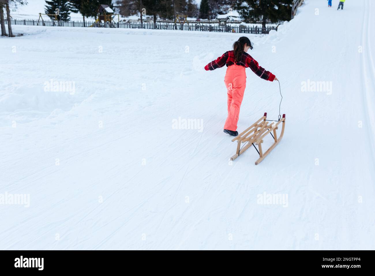 girl with dark long hair in red pullover and orange ski pants running ...