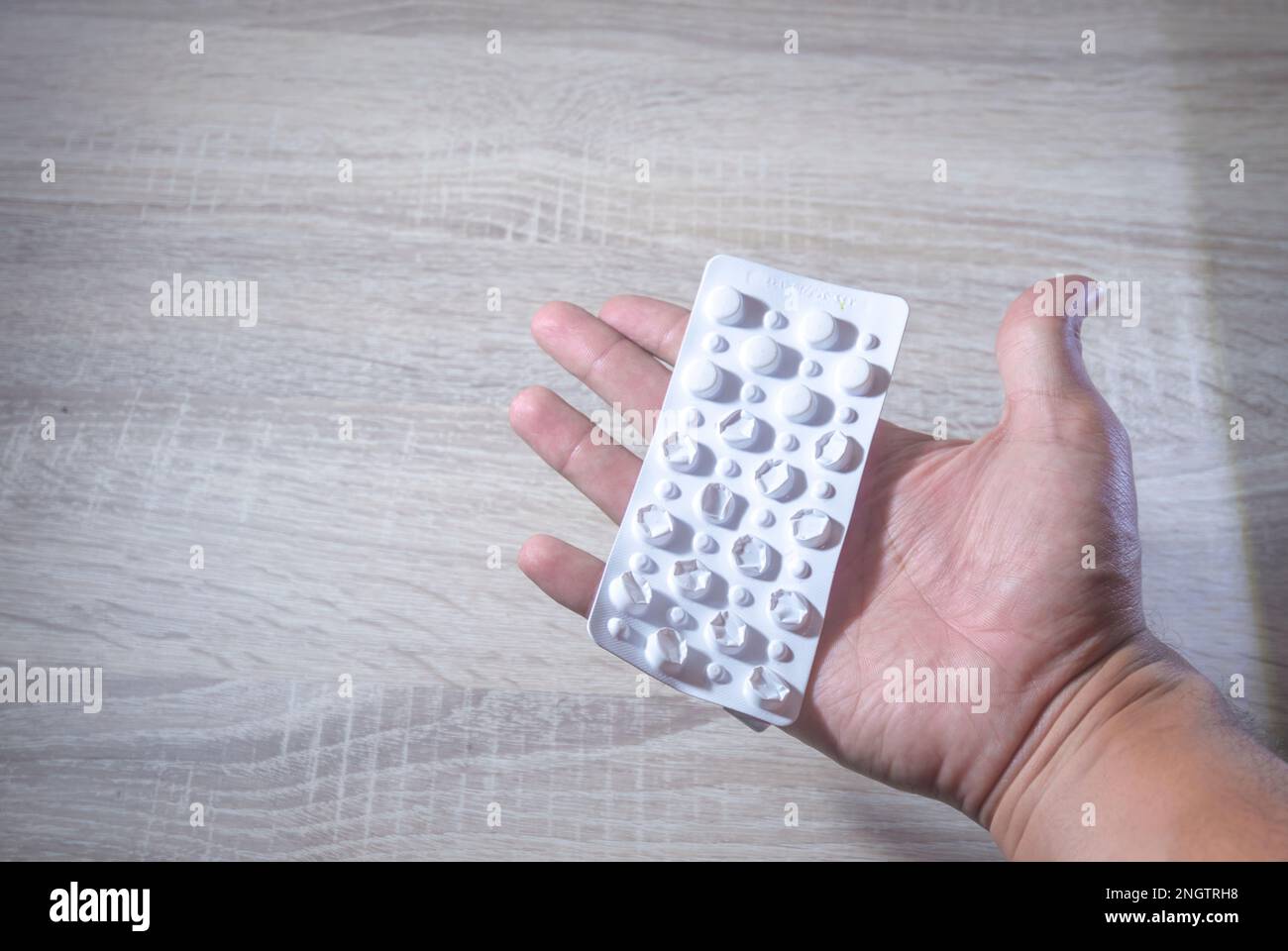 Human hand holding medicine pills,light wood background Stock Photo - Alamy