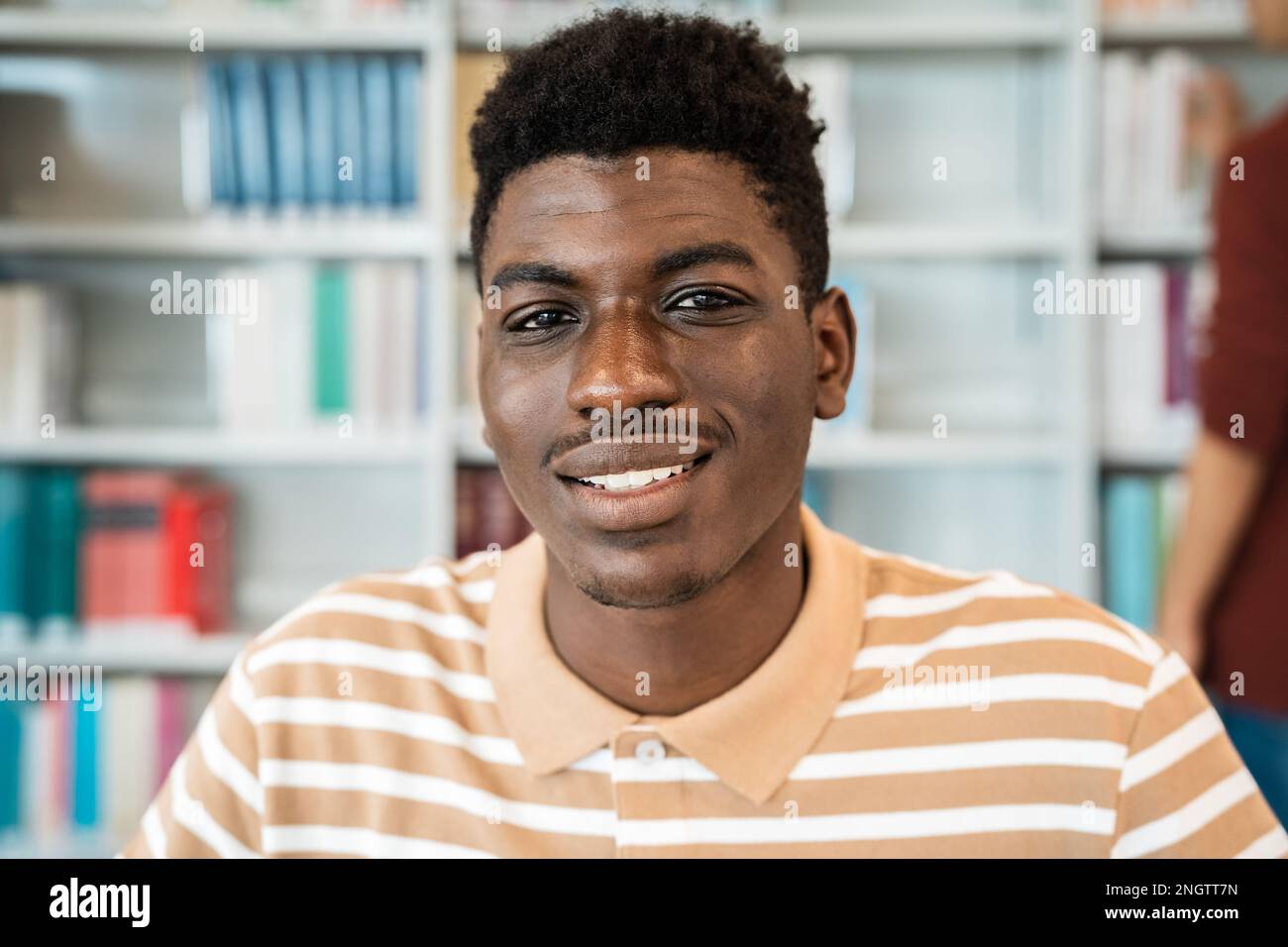 Happy young African man smiling into the camera while standing inside ...