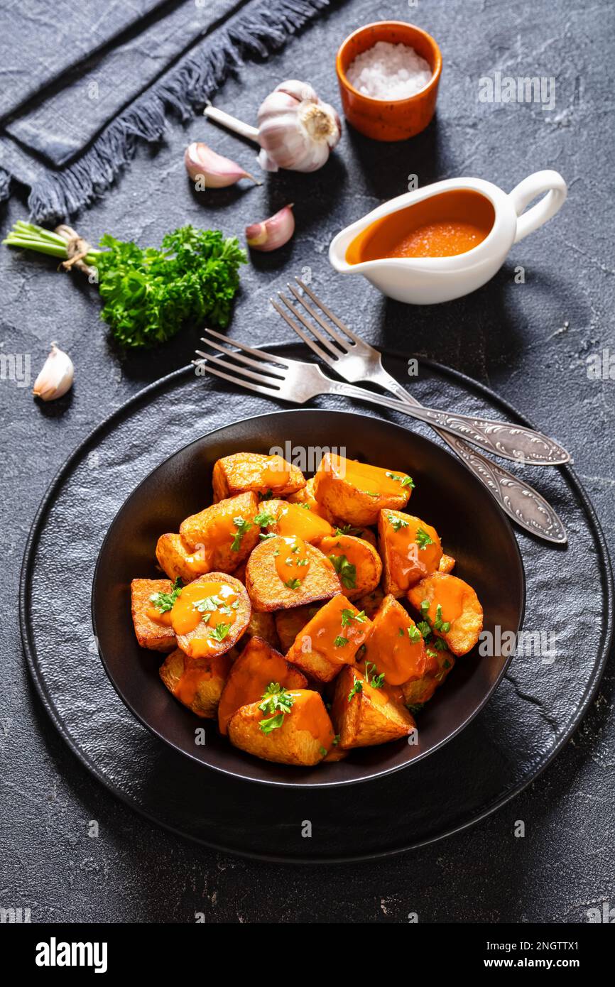 patatas bravas, deep fried potatoes with spicy sauce in black bowl on ...