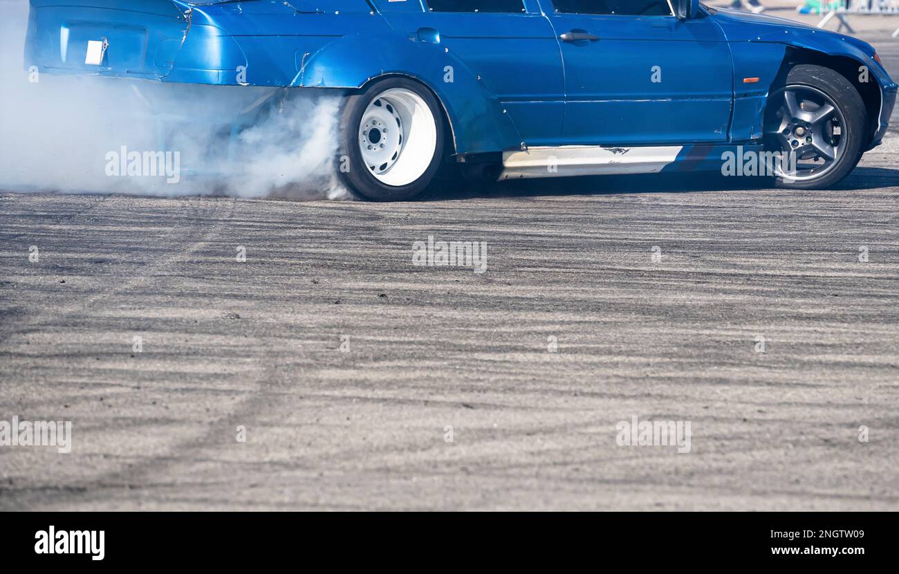 closeup side view of blue sport car drifting on gray speed tarmac track ...
