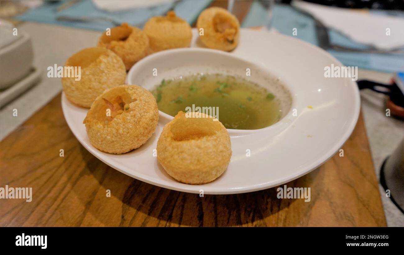 Pani Puri or Golgappa or Puchkas from a white plate which is popular ...
