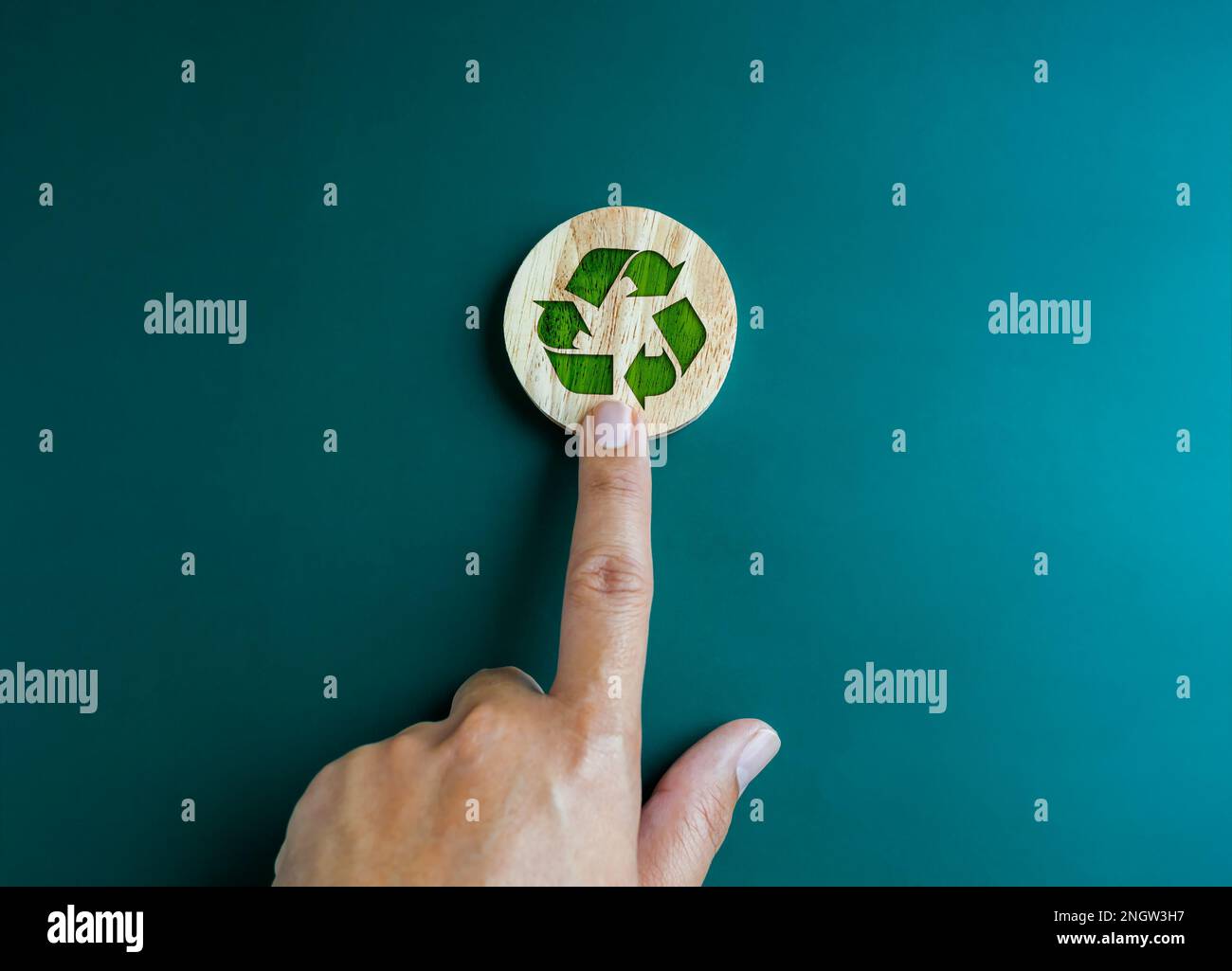 Green recycle icon symbol on round wooden block, pointing by hand ...
