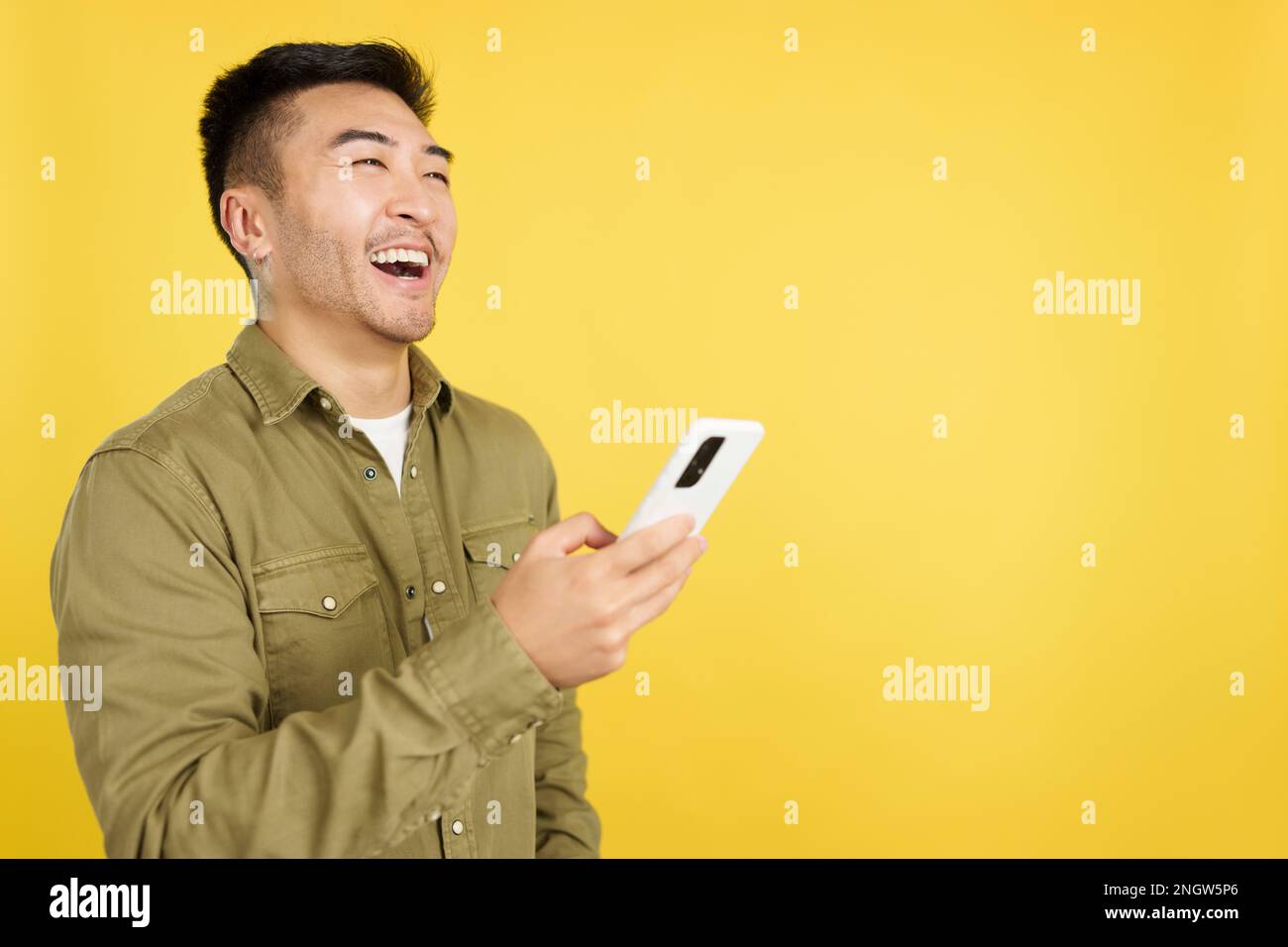 Happy chinese man laughing while using the mobile Stock Photo - Alamy
