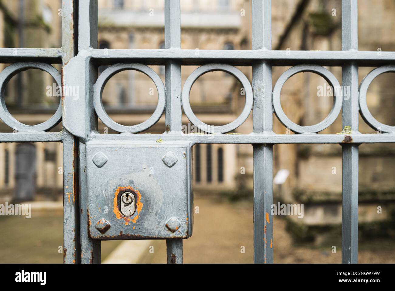 Close up of an ornate metal gate seen locked. The background shows part ...