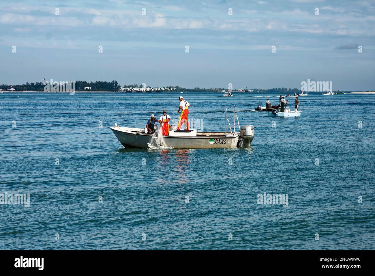 many boats anchored, men fishing, pulling up net with fish, sport ...