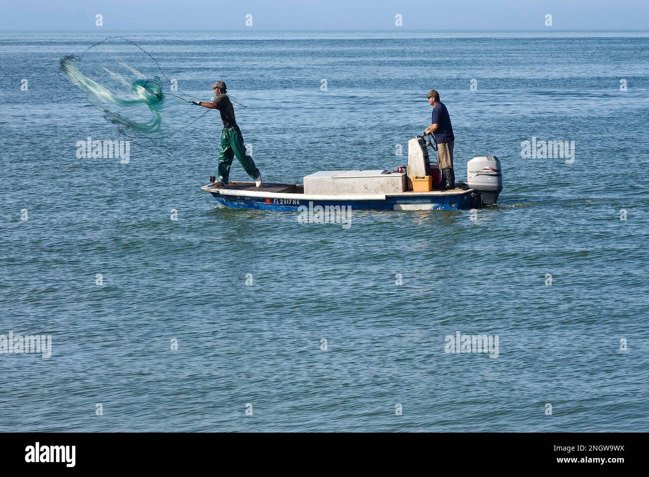 Boat moving slowly, men fishing, throwing net, sport, motion ...