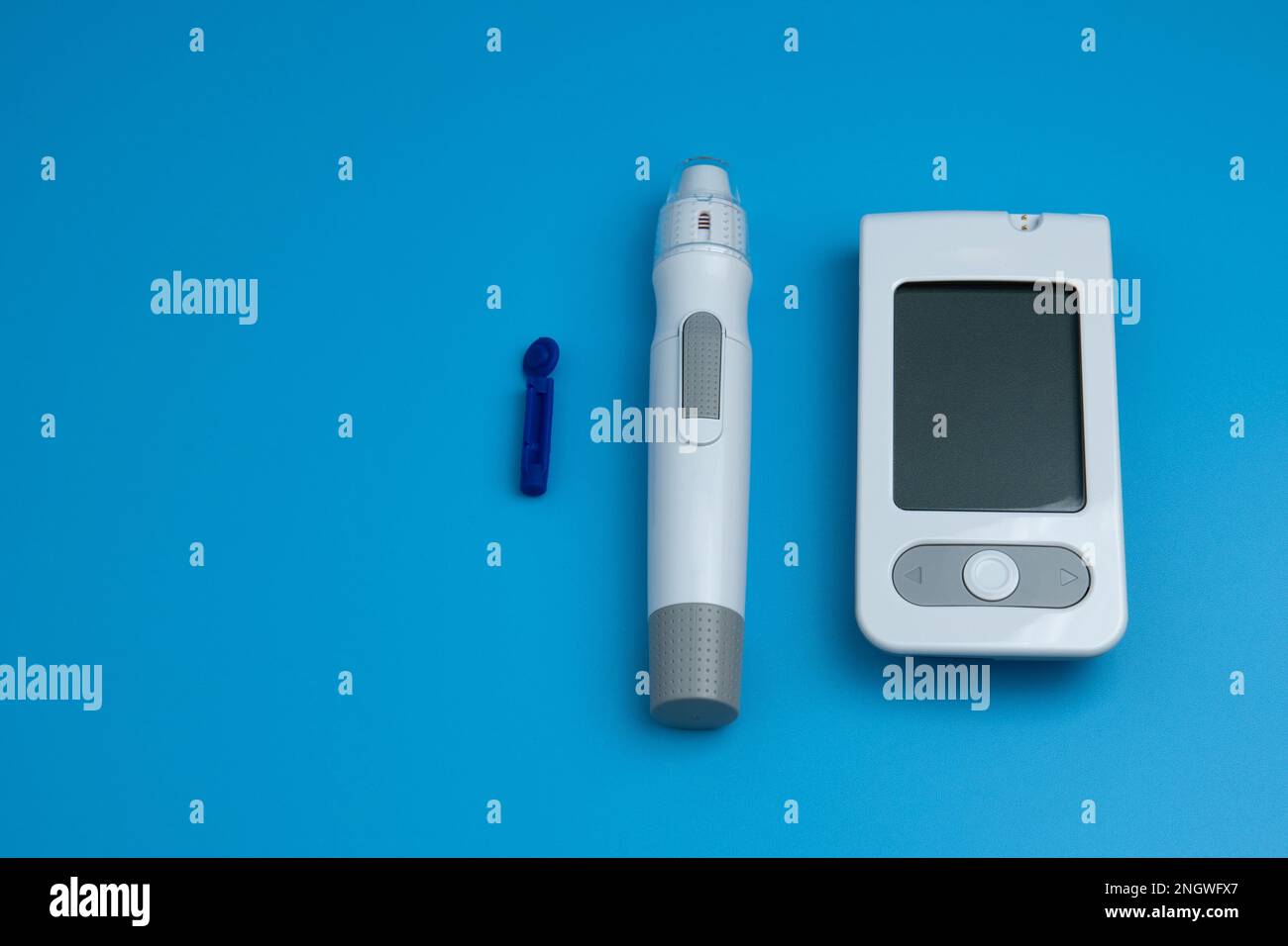 The digital glucometer and lancet pen are isolated on blue background ...