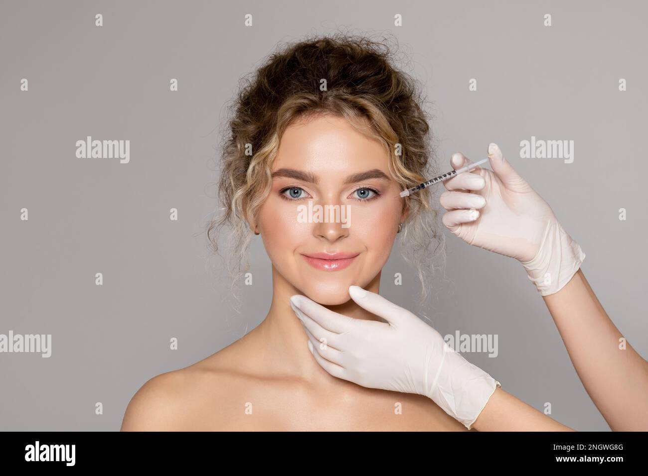 Cosmetologist doctor making botox injection for eyes area to young lady ...