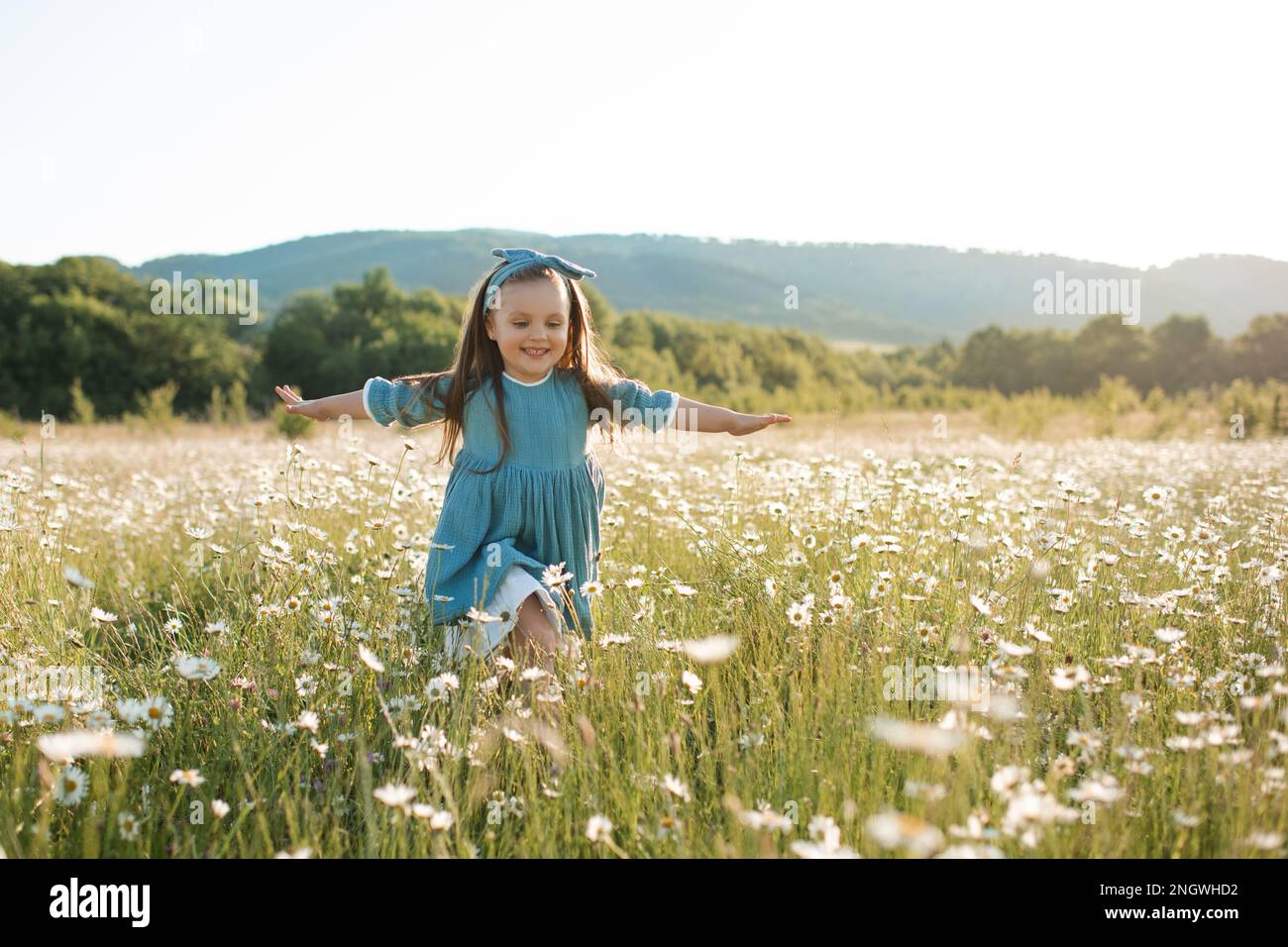 Happy cheerful child girl 3-4 year old walk in chamomile meadow having ...
