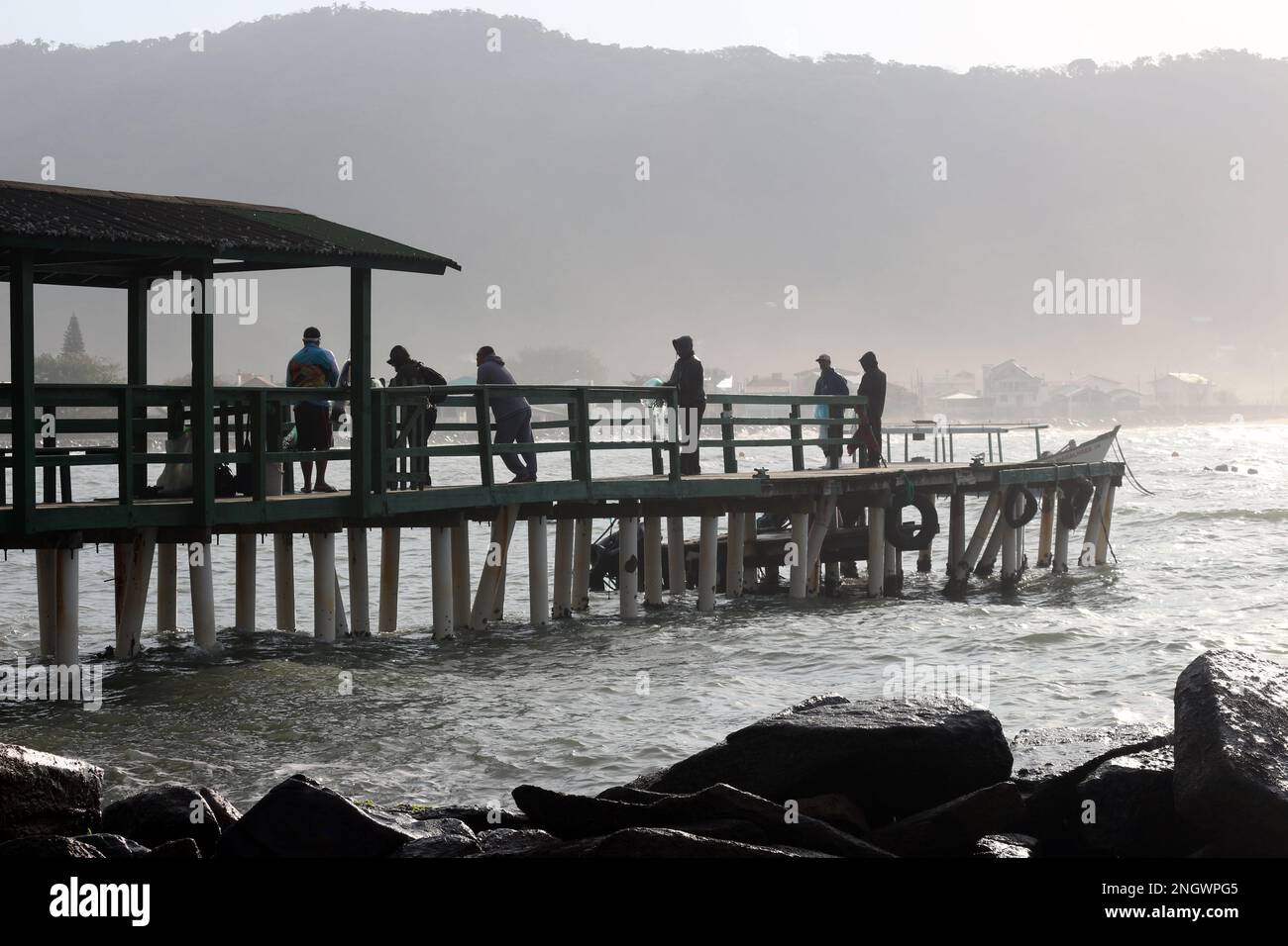 At dusk, fishermen on the pier wait for the right time to cast the net ...