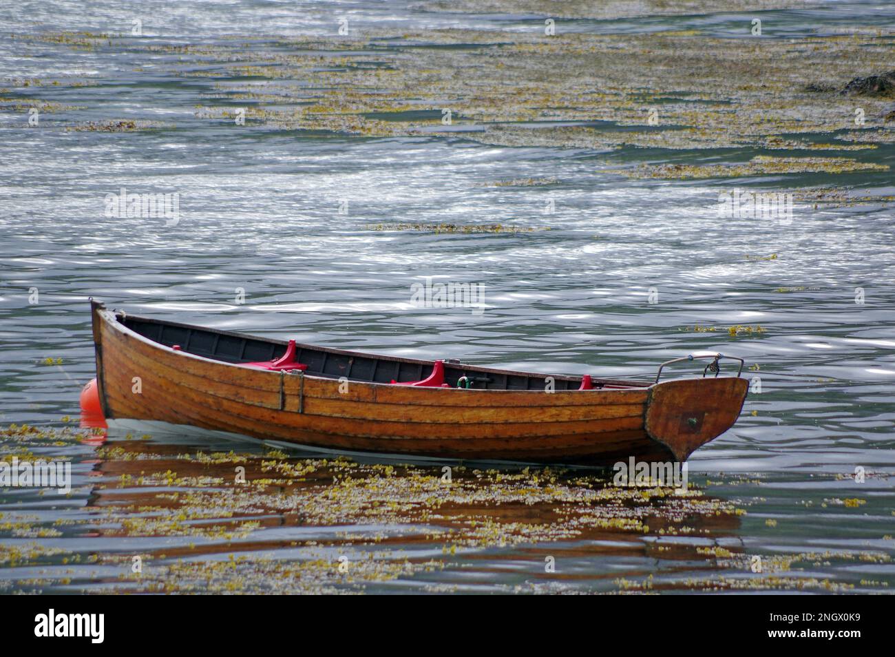 Small wooden rowing boat lying in the shallow waters of Plockton ...