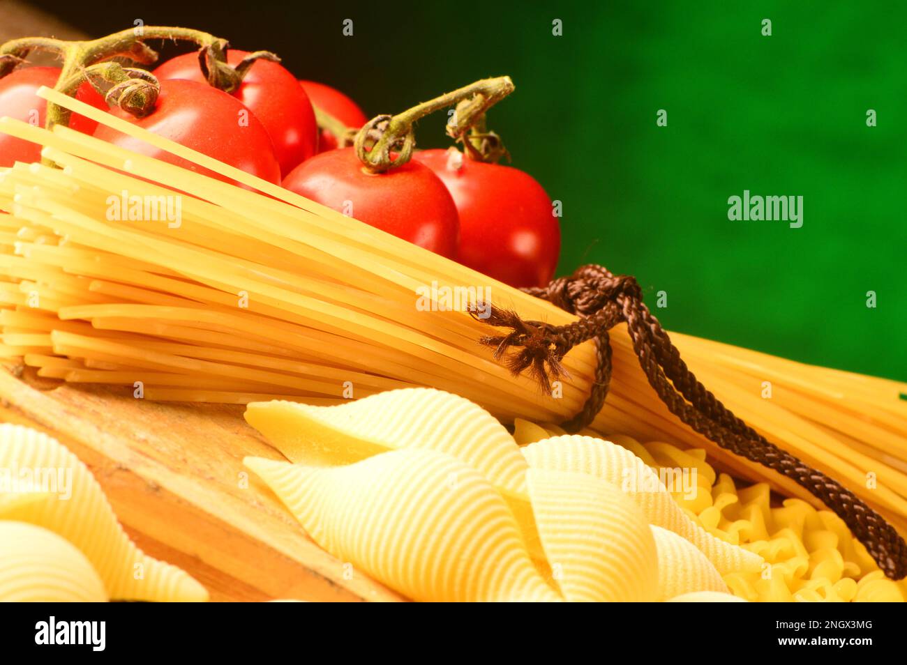 still life with variety of pasta and tomatoes over green gradient Stock ...
