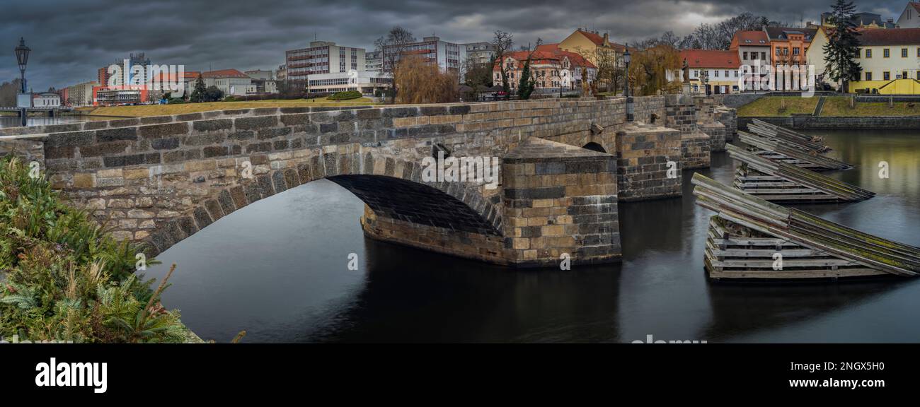 Old stone bridge and center of Pisek town in cloudy winter windy ...