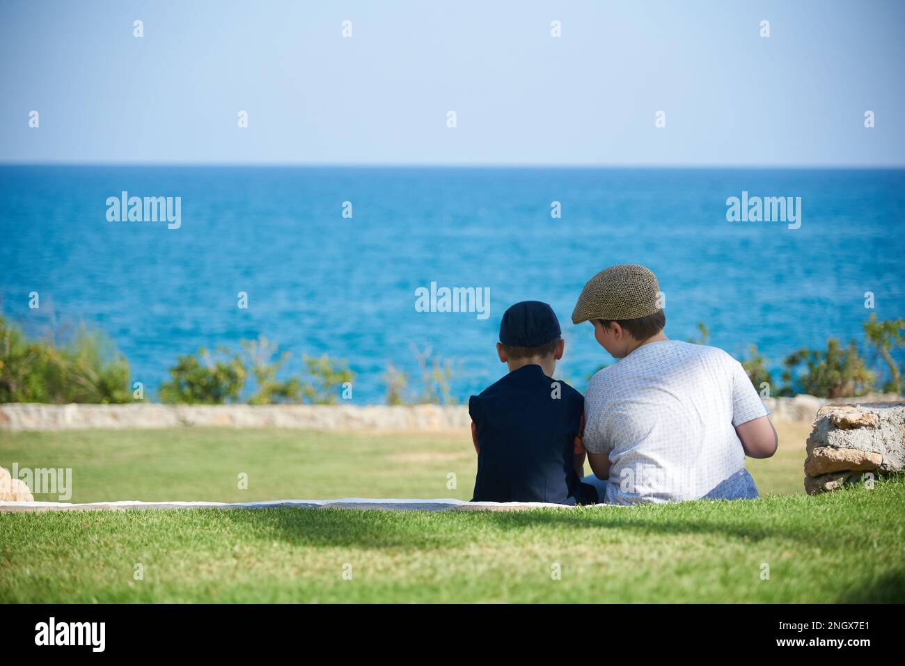 two children talking in a garden in front of the sea Stock Photo - Alamy