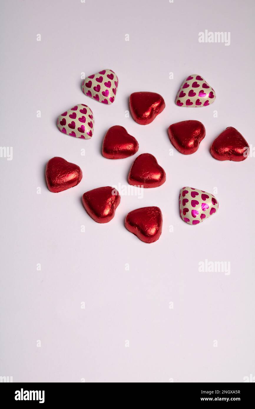 photo of chocolates in a red wrapper in the shape of hearts on a white ...