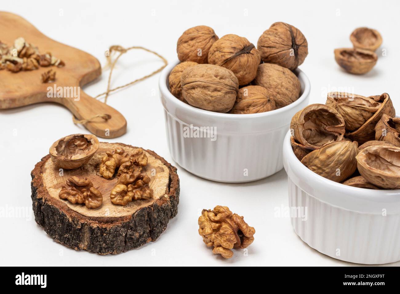 Nutshells and whole nuts in white bowls. Walnut kernels on a stump. Top ...