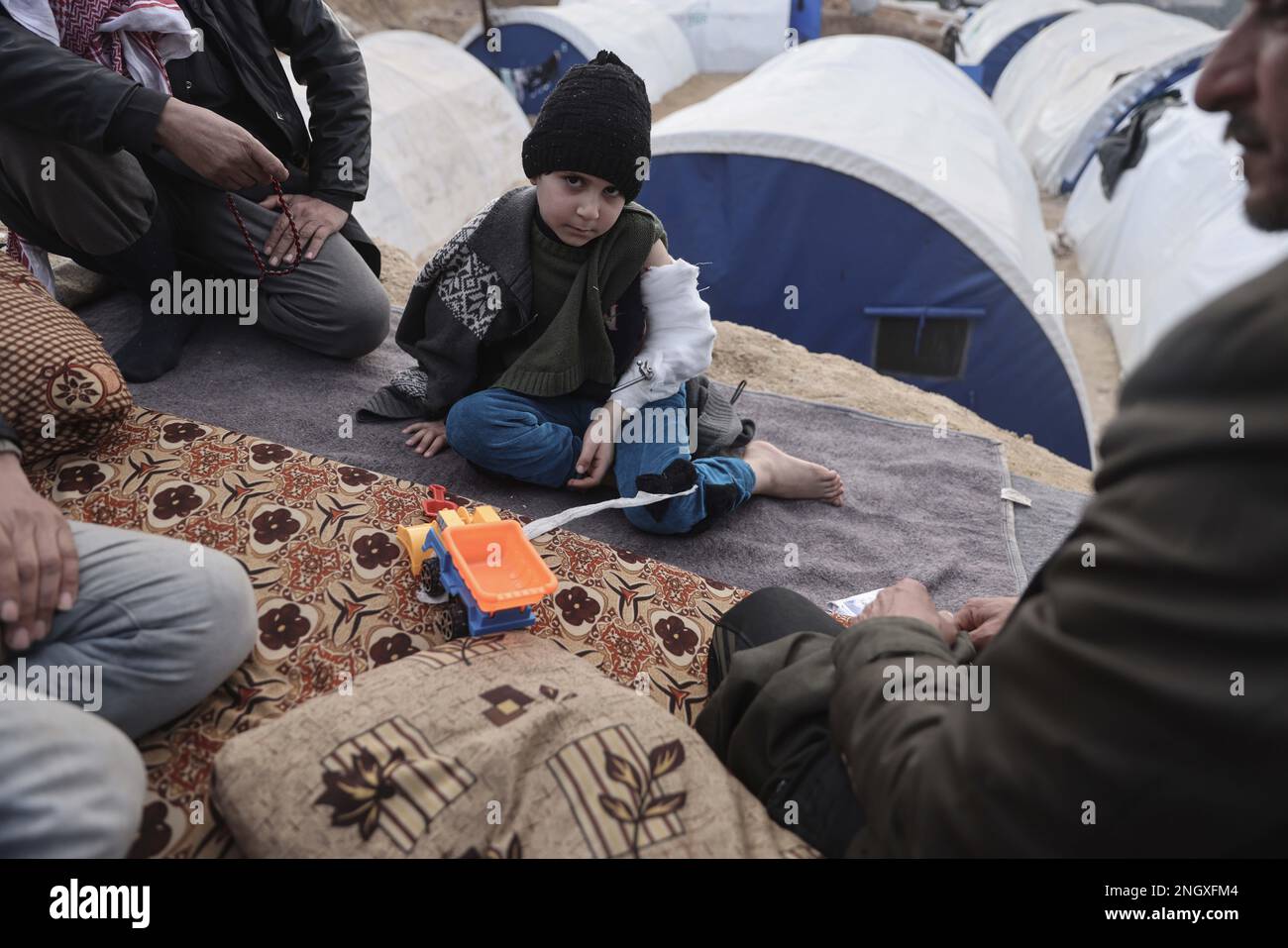 Salqin, Syria. 19th Feb, 2023. An injured child sits with his family at ...