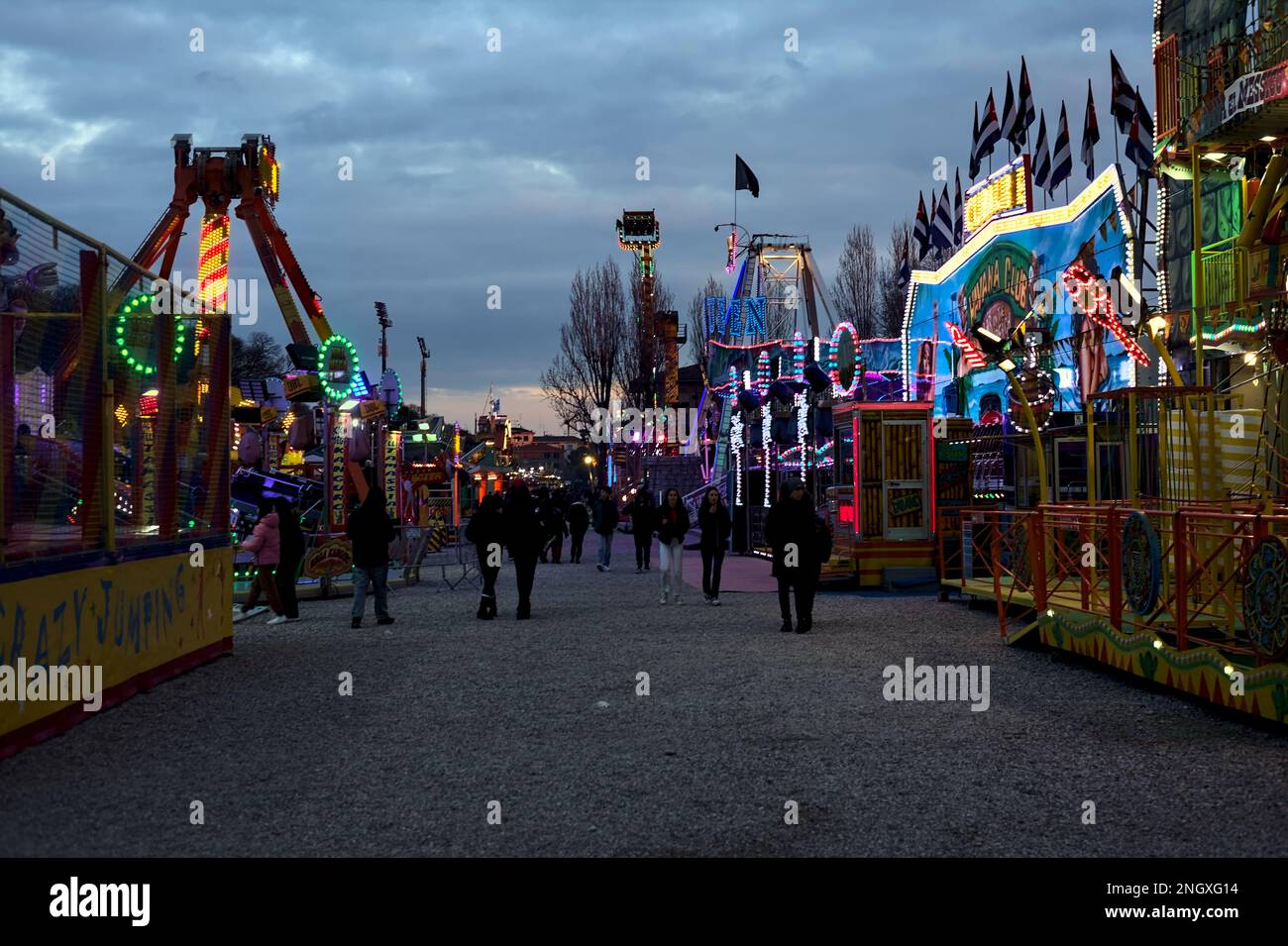 Rides in a fair at dusk with people passing by Stock Photo - Alamy