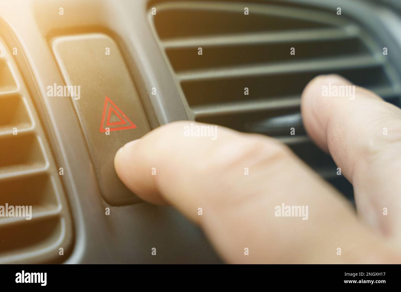 A man presses the alarm button on the dashboard of a car. Close-up ...