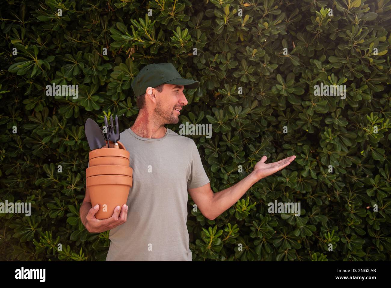 Man gardener in green cap holds terracotta clay pots with gardening ...