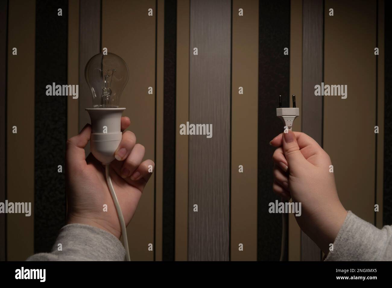Human in a dark room holds a holder with a light bulb in one hand and ...