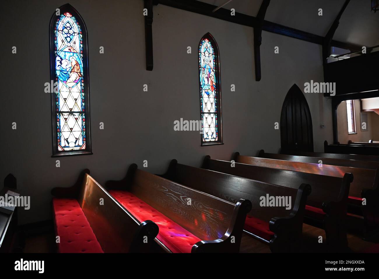 Sunlight streams through stain glass windows onto pews at the Holy ...