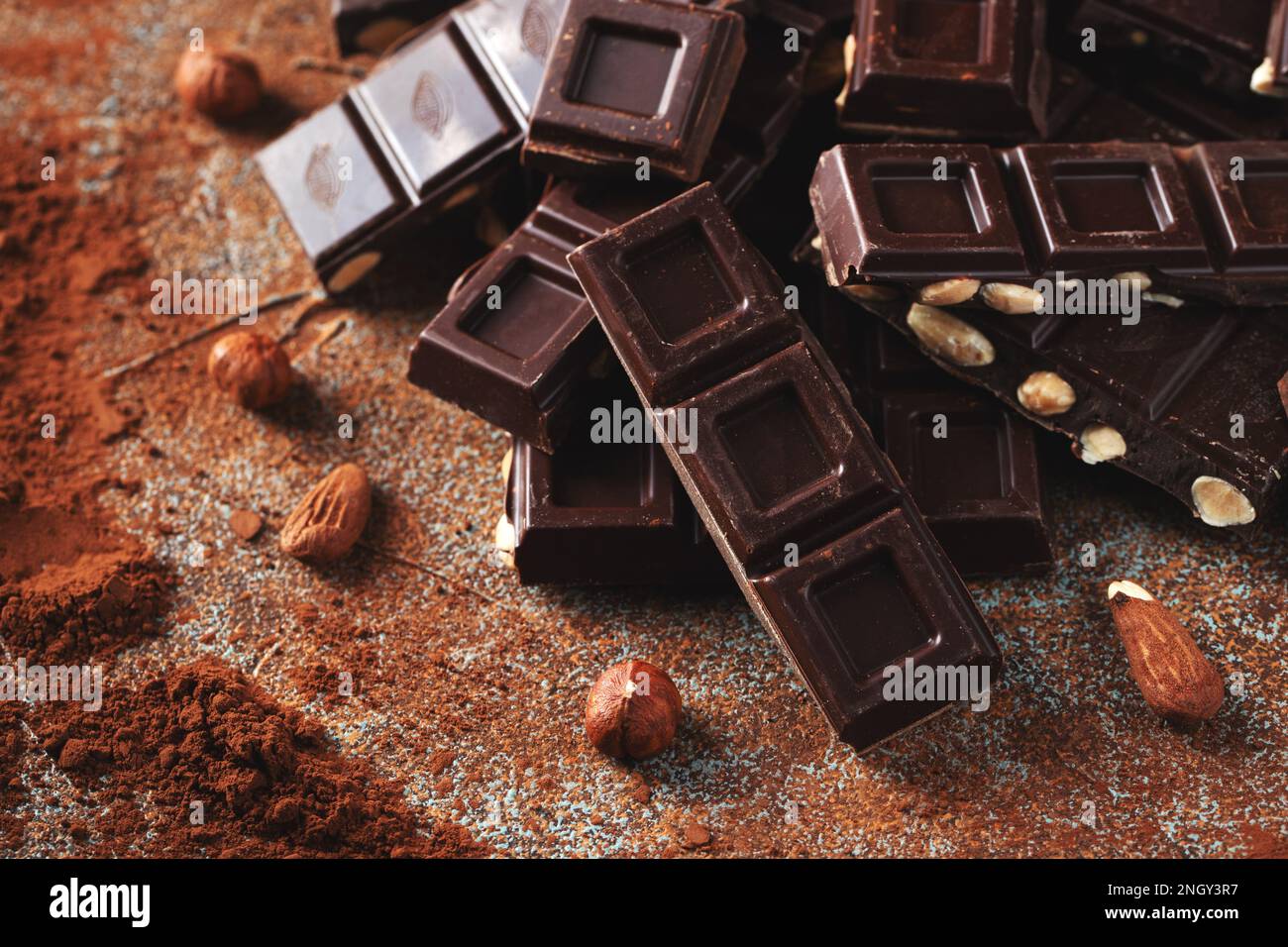 Dark and milk chocolate with nuts on a dark background sprinkled with ...