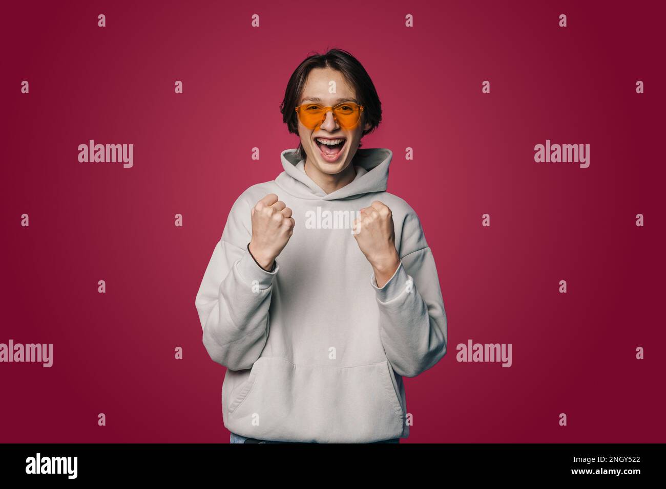 Happy joyful young man wearing eyeglasses doing winner gesture ...