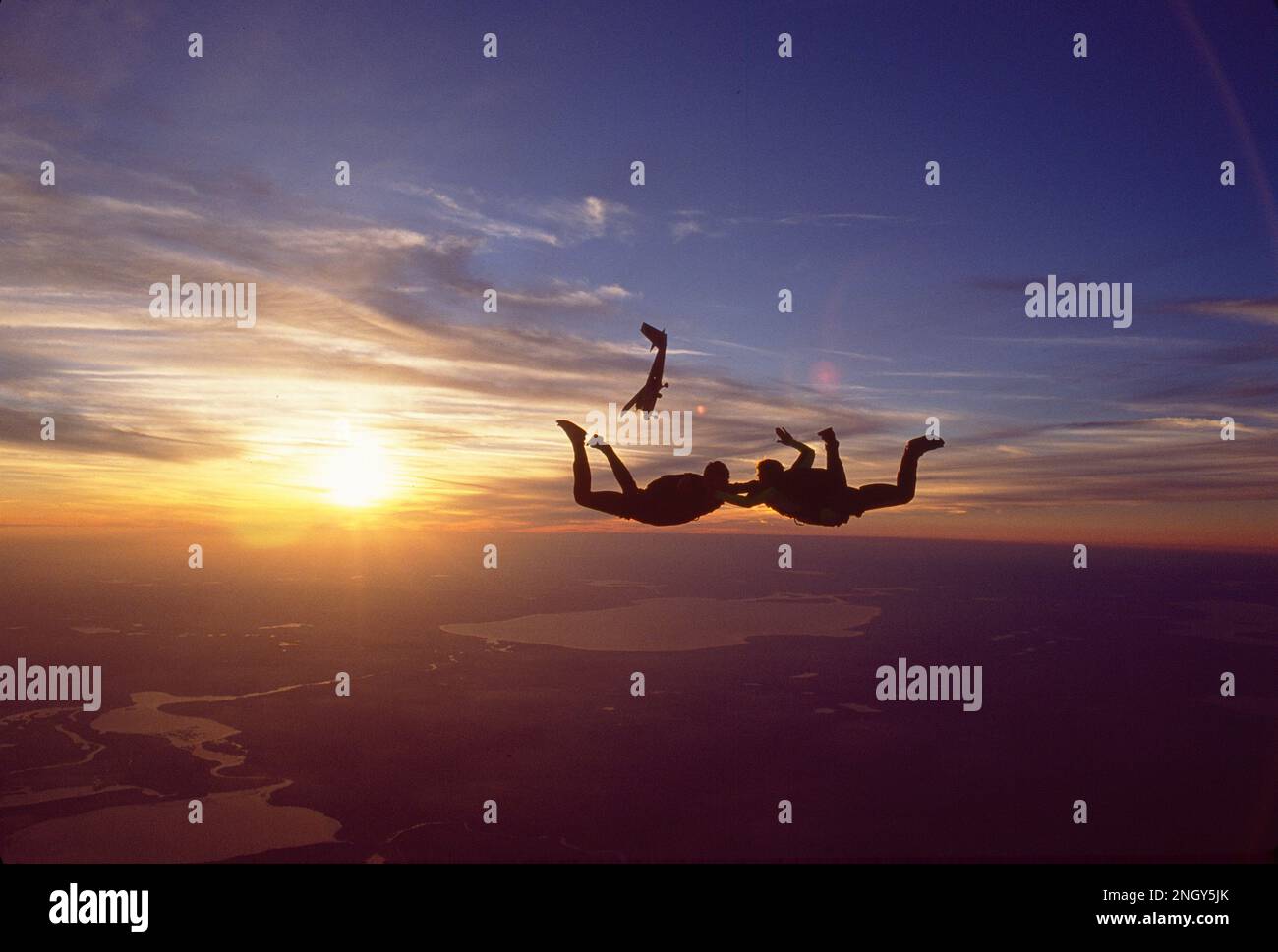 Pair of skydivers holding hands while freefalling showing airplane ...