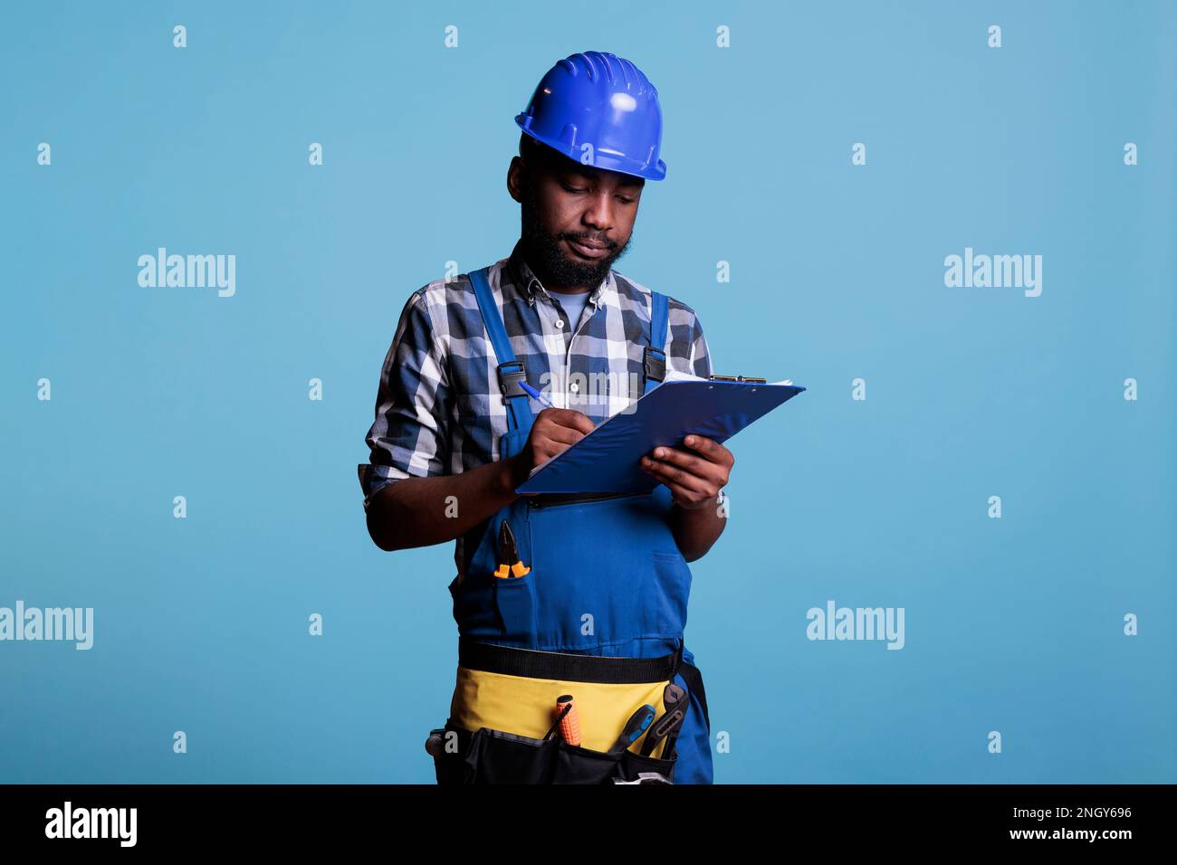 Construction supervisor writing on clipboard supervising building ...