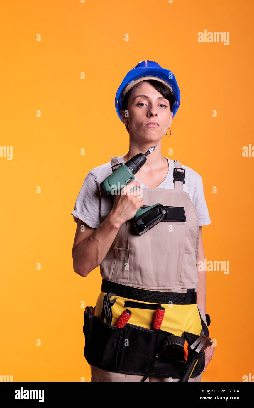 Female industrial builder holding power drill gun in front of camera ...