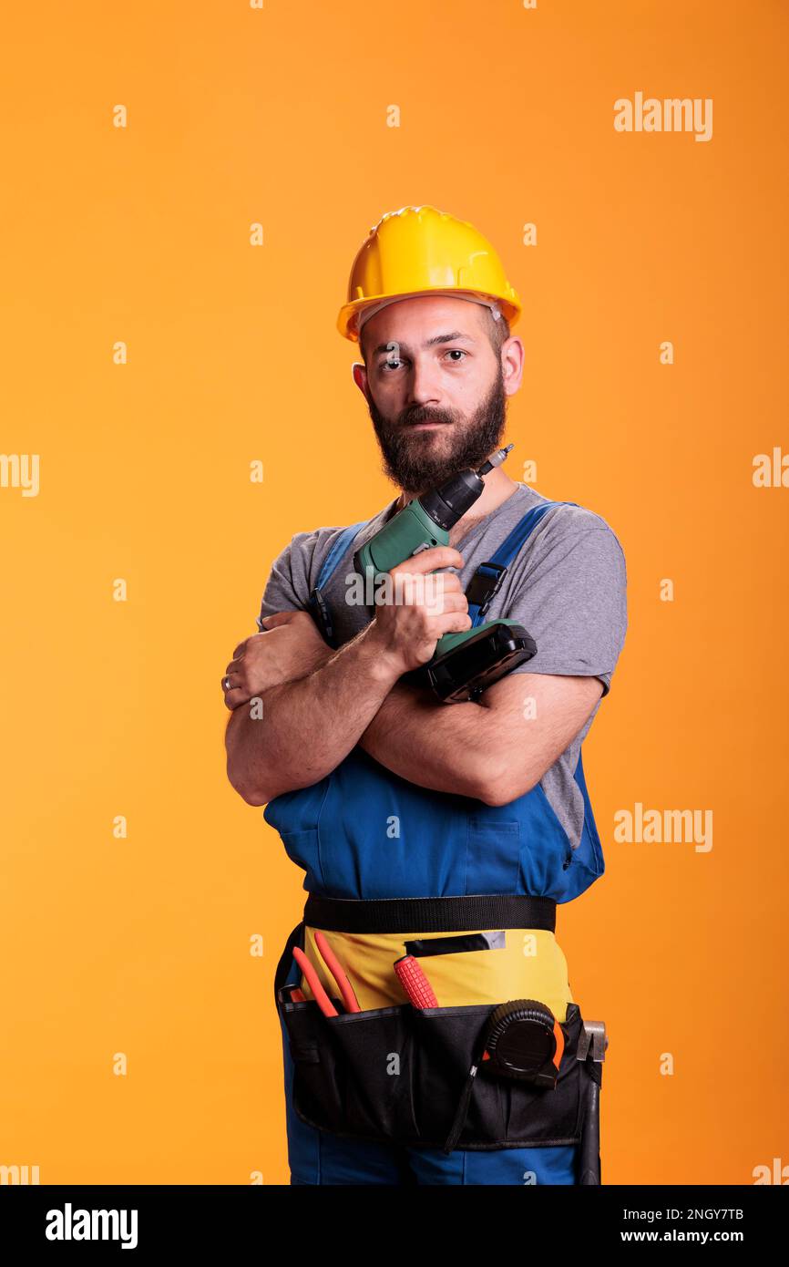 Engineering repairman holding cordless electric drill, posing in studio ...