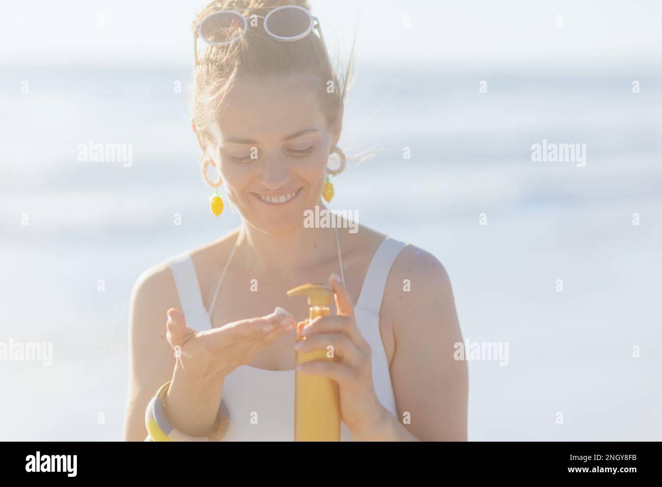 smiling modern woman in white swimsuit with spf at the beach Stock ...
