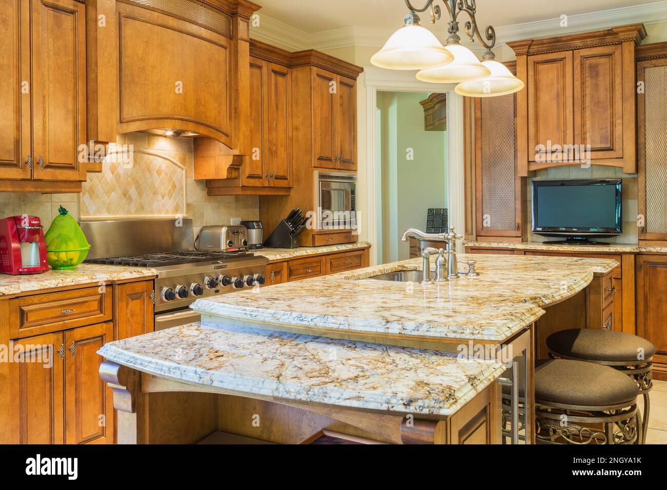 Wooden cabinets and island with tan nuanced quartz countertop padded ...