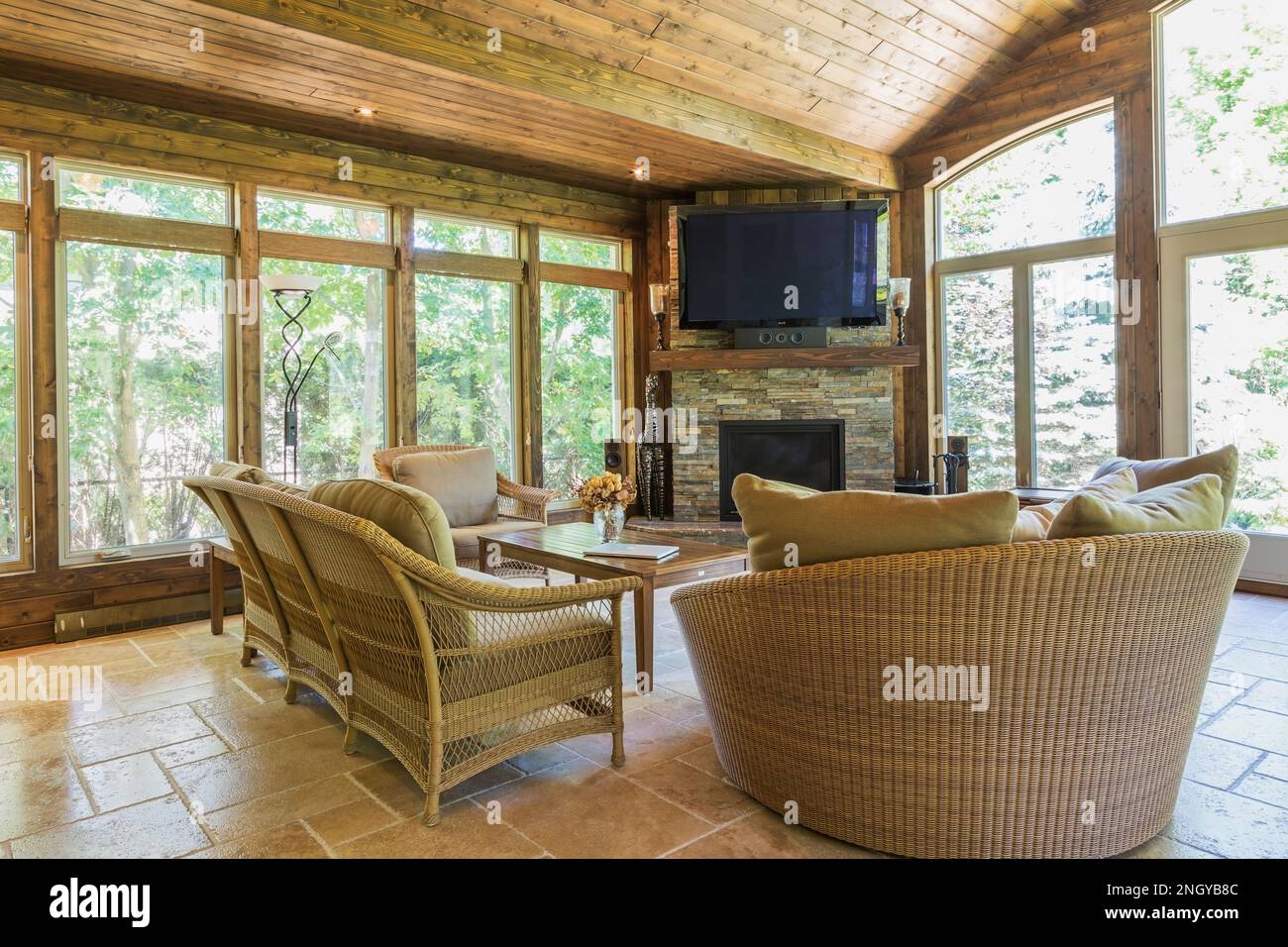 Wicker chairs and sofa in solarium with tan marble tile floor, stone ...