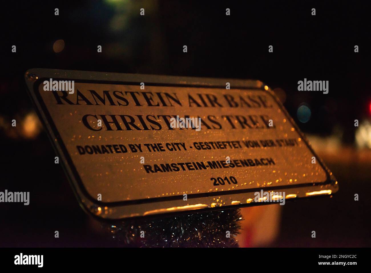 A plaque glistens in the rain in front of a Christmas tree before a ...
