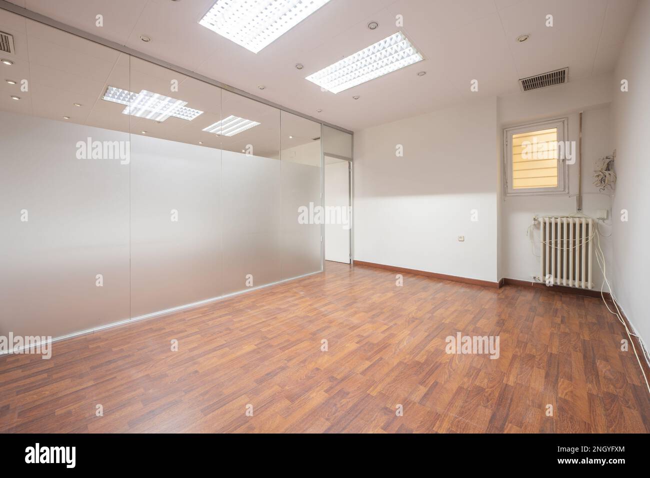 An empty office with a wall of glass partitions, jatoba-colored ...