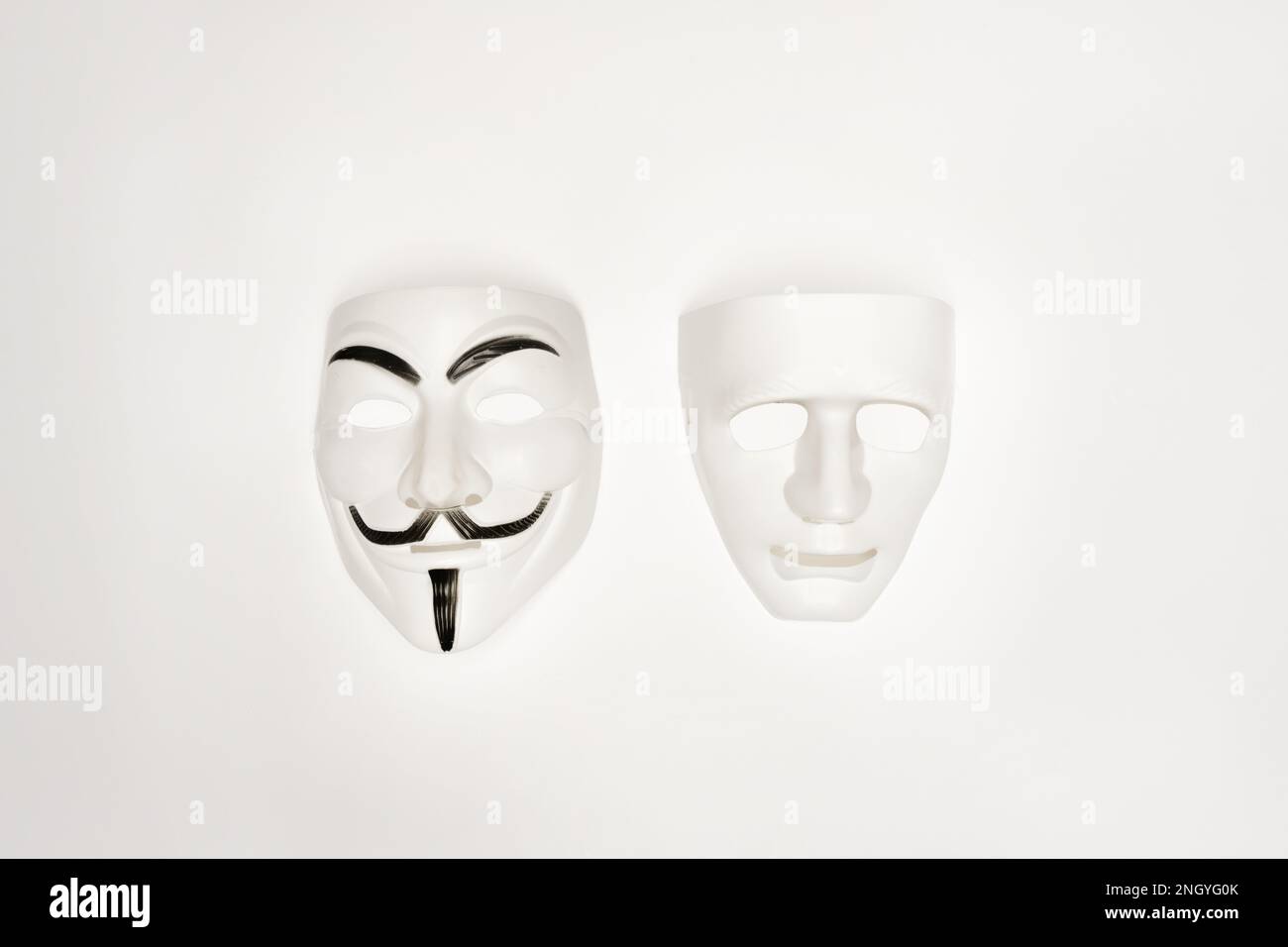 An expressionless white mask on a smooth white surface next to another ...