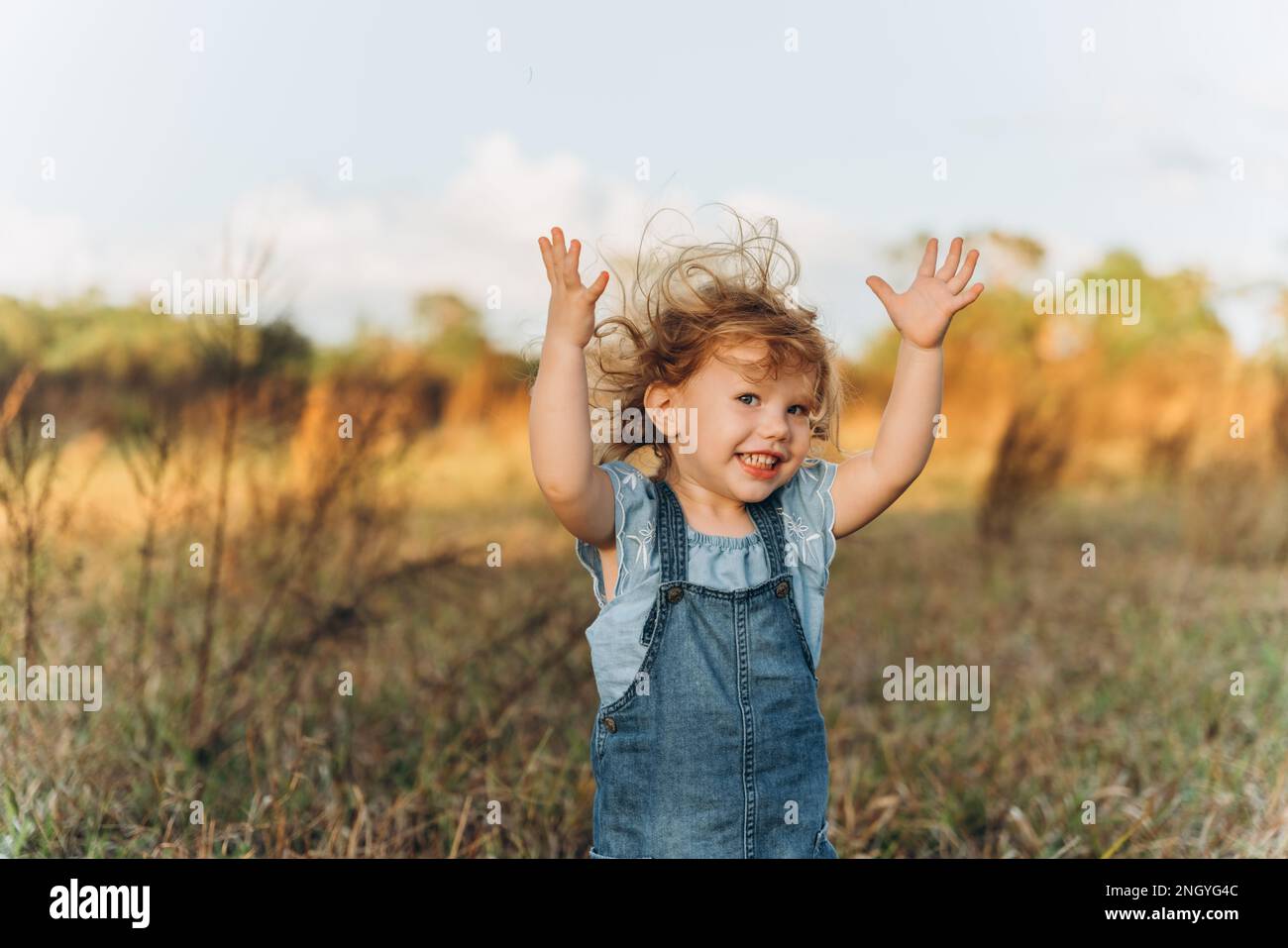 Cute red head 2 years old smiling girl with hands raised up Stock Photo ...