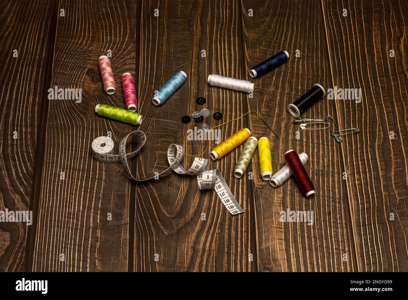 A composition of sewing items with various spools of colored thread, a ...
