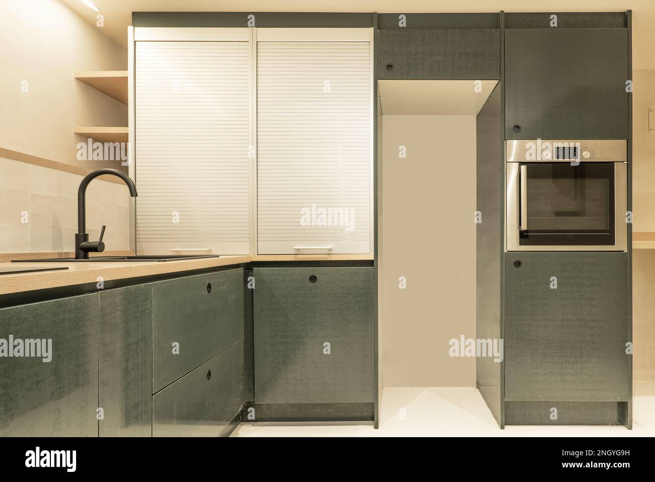Kitchen with green cabinets, black handles, a cabinet with closed ...