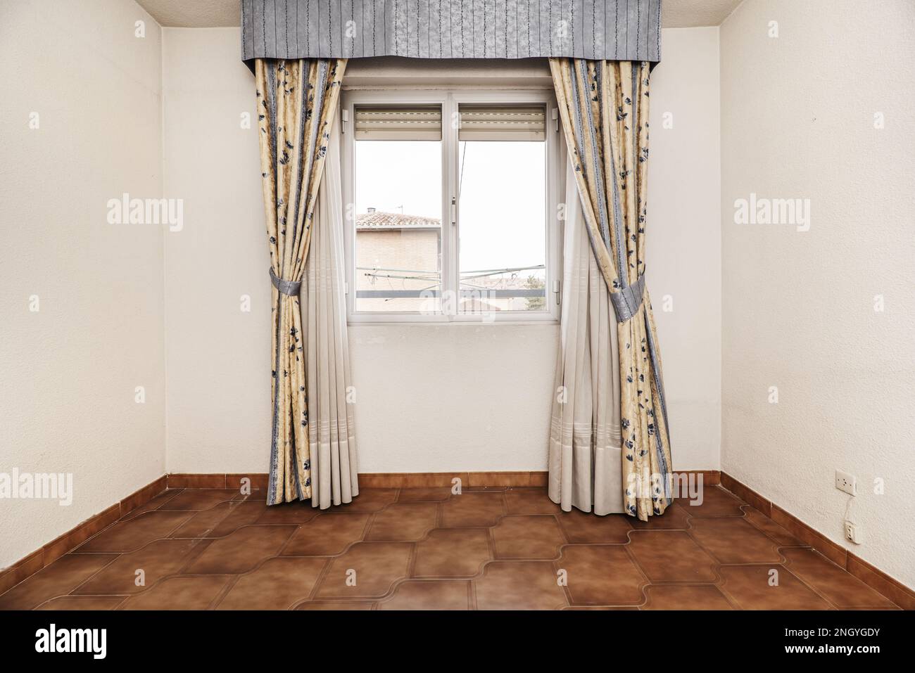 Empty room with dark stoneware floors and window with patterned ...