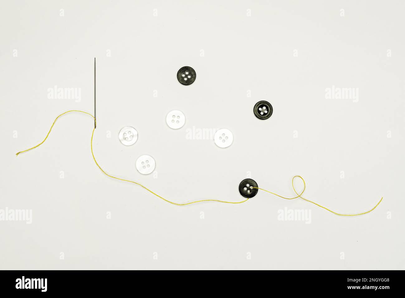 Needle with threaded yellow thread passing the thread through a black ...