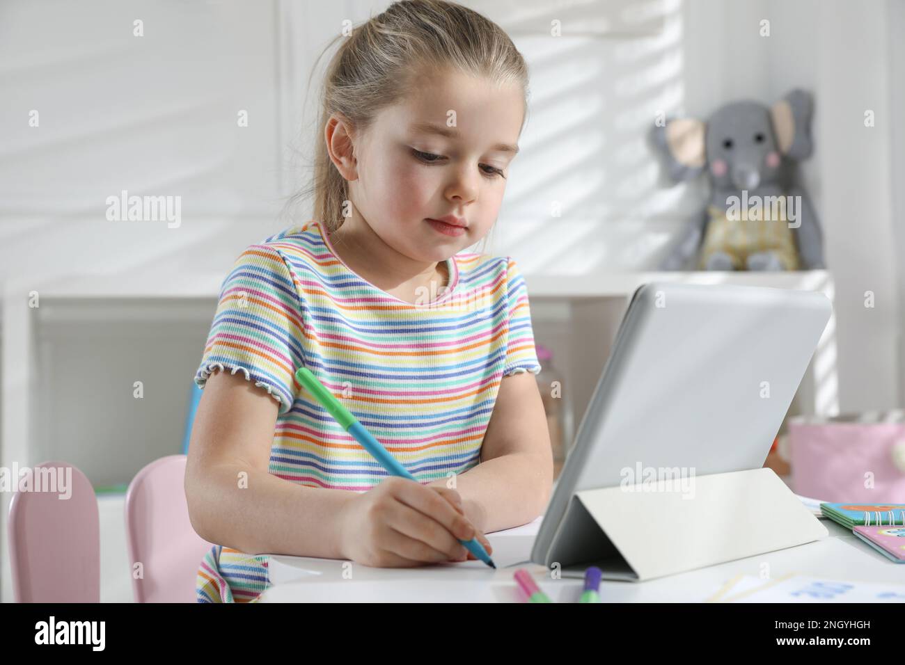Little girl learning English with tablet indoors at online lesson Stock ...