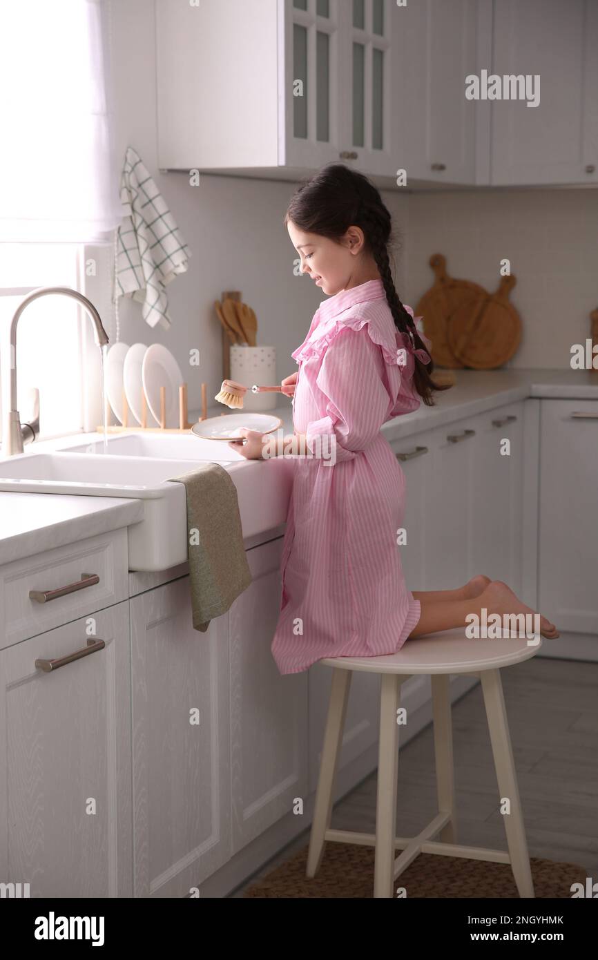 Little girl washing dishes in kitchen at home Stock Photo - Alamy