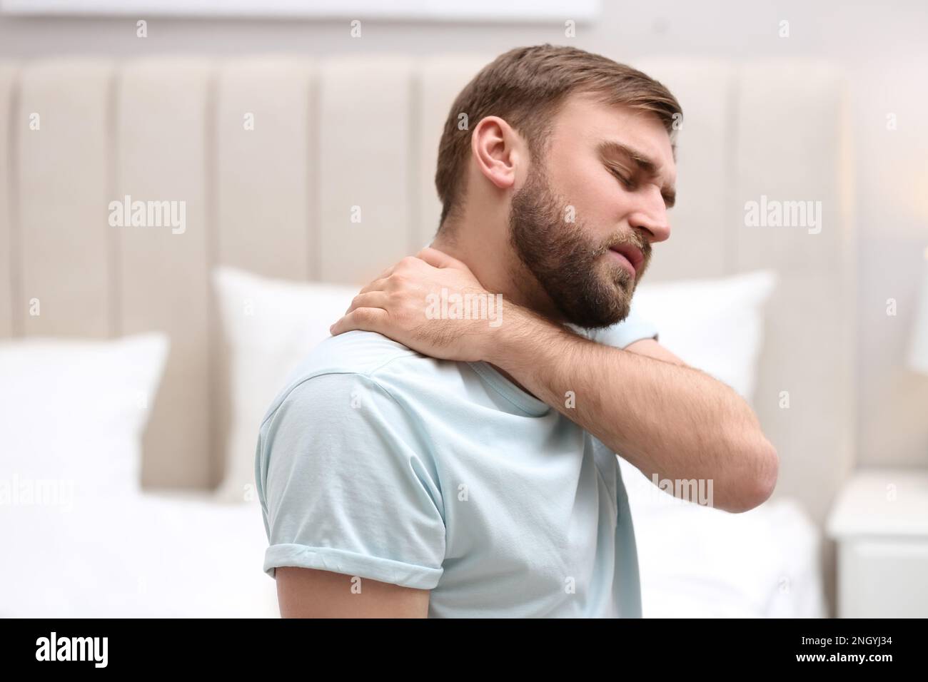 Man suffering from neck pain at home. Bad posture problem Stock Photo ...