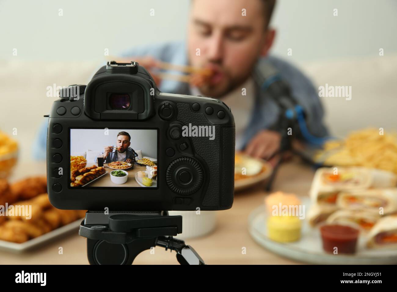 Food blogger recording eating show against light background, focus on ...