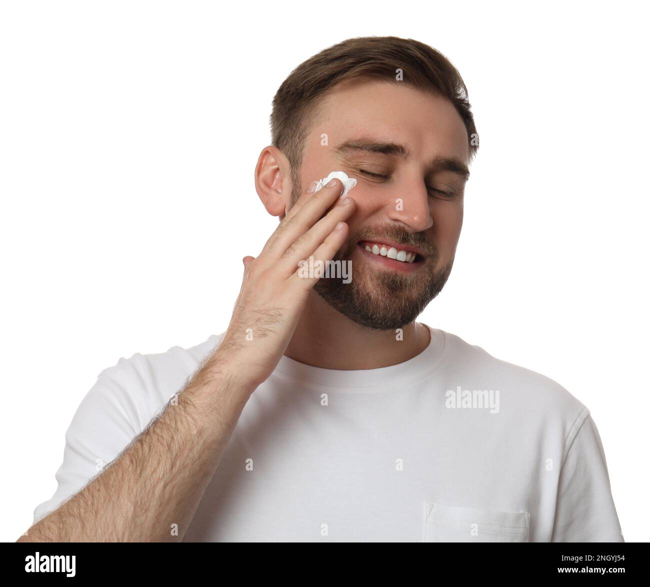 Happy young man applying facial cream on white background Stock Photo ...